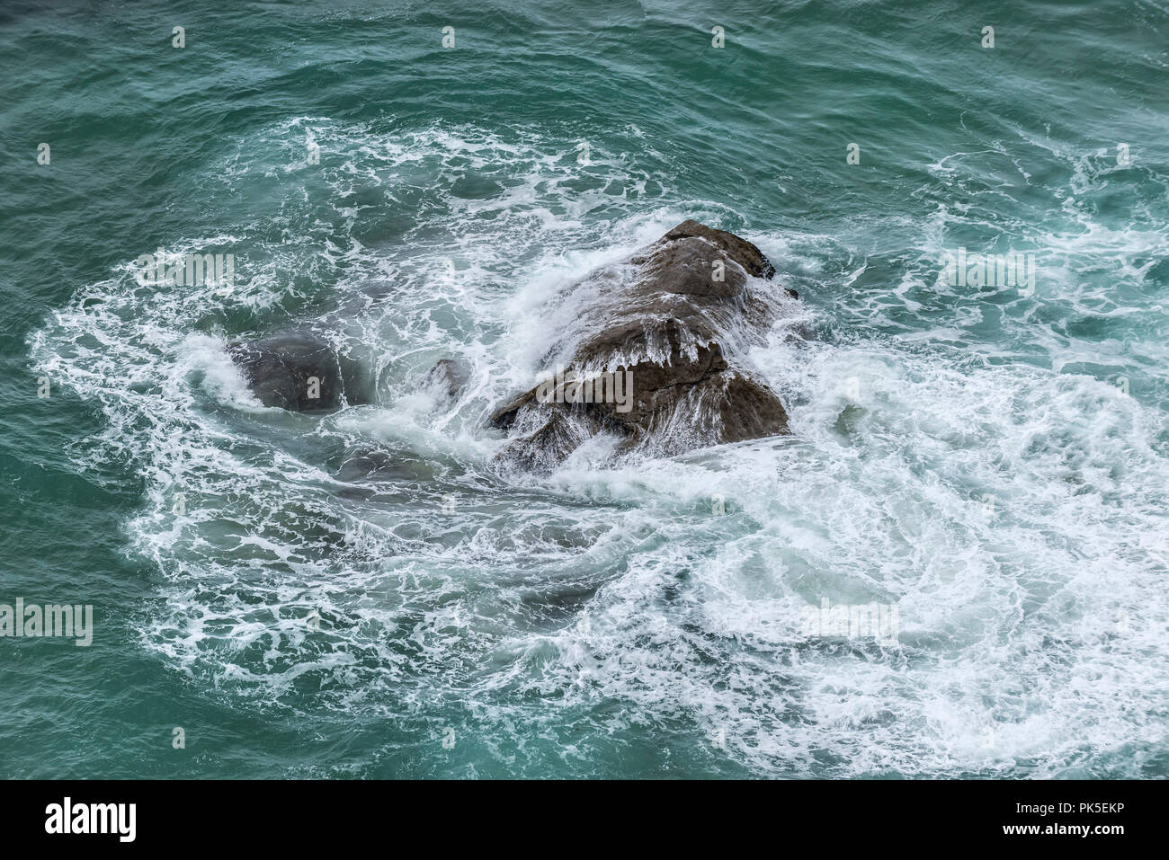 Incoming tide; swirling around a large rock in the sea Stock Photo - Alamy