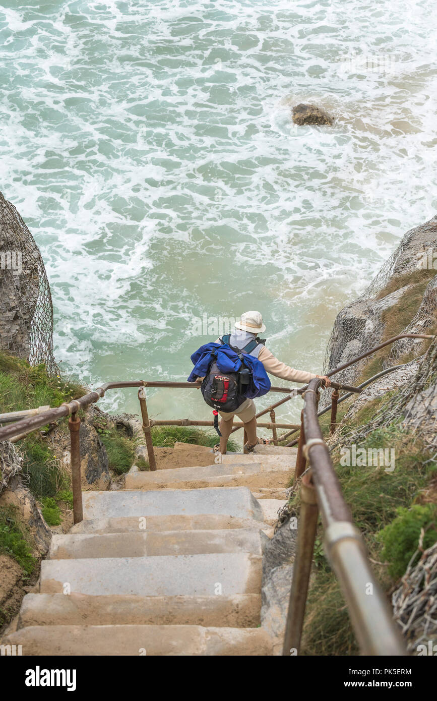 A mature walker carefully climbing down steep steps leading down to ...