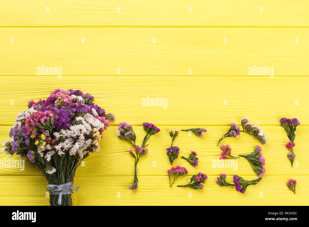 Bouquet of statice flowers and word yes. Top view, copyspace. Yellow ...