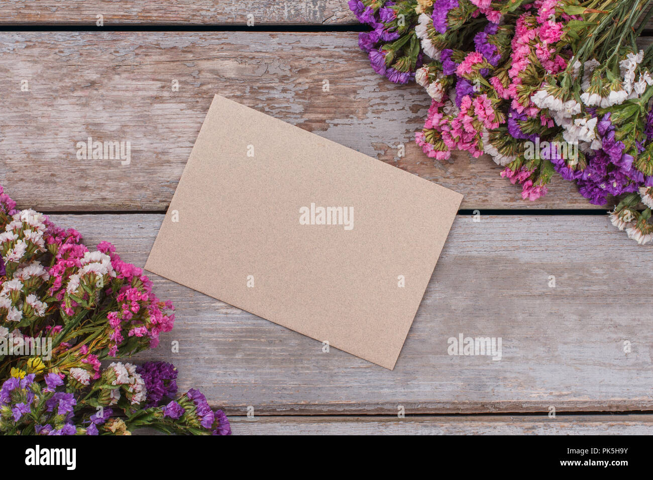 Blank cardboard and flowers on wood. Flat lay, top view. Wooden desk ... Blank cardboard and flowers on wood. Flat lay, top view. Wooden desk ...