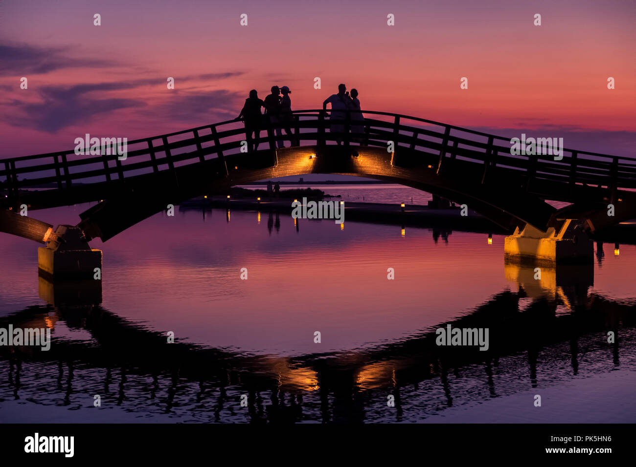 Silhouettes and reflections as tourists enjoying a beautiful sunset ...