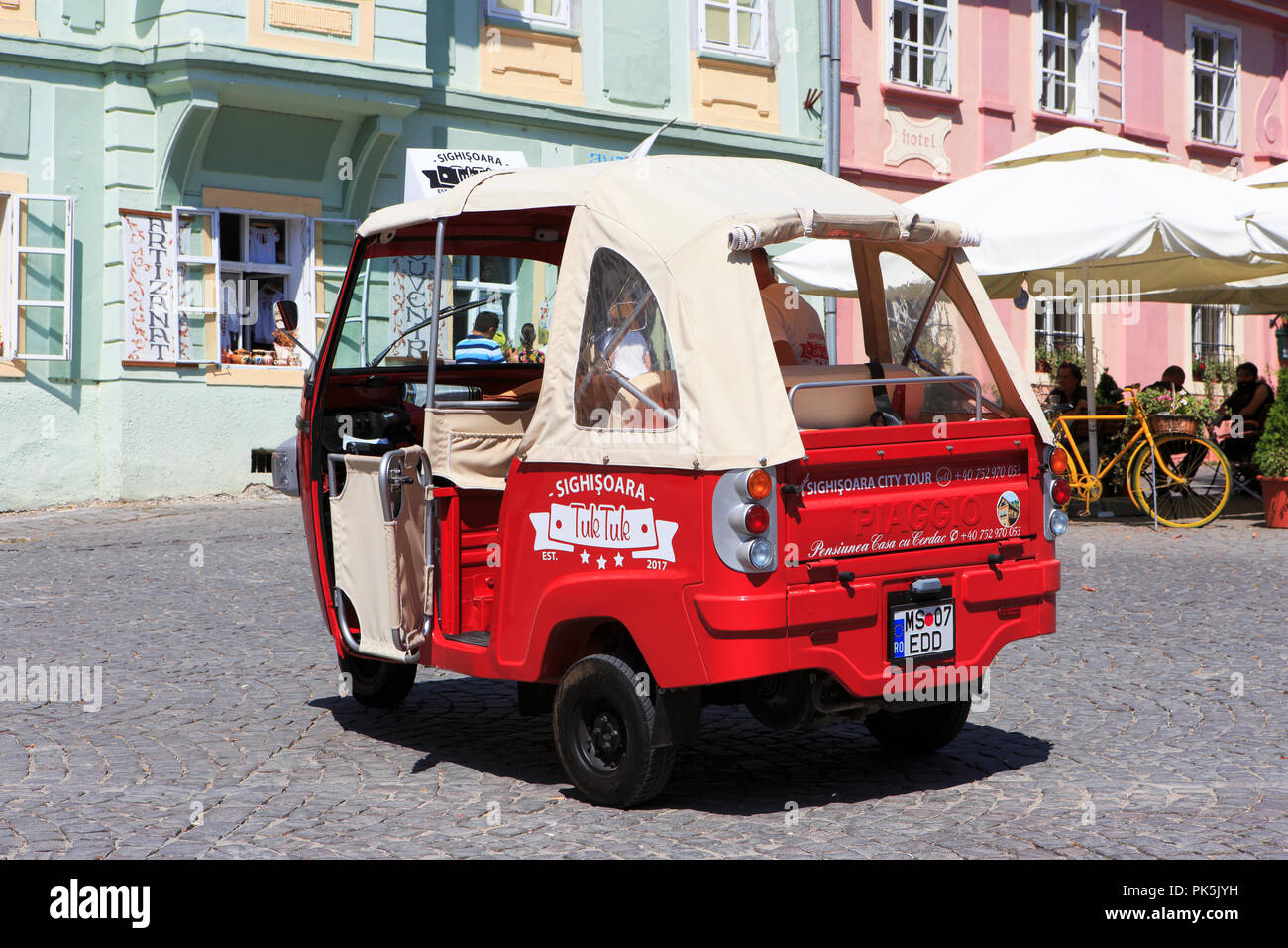 A red tuk tuk (auto rickshaw) waiting for the next ride in Sighisoara ...