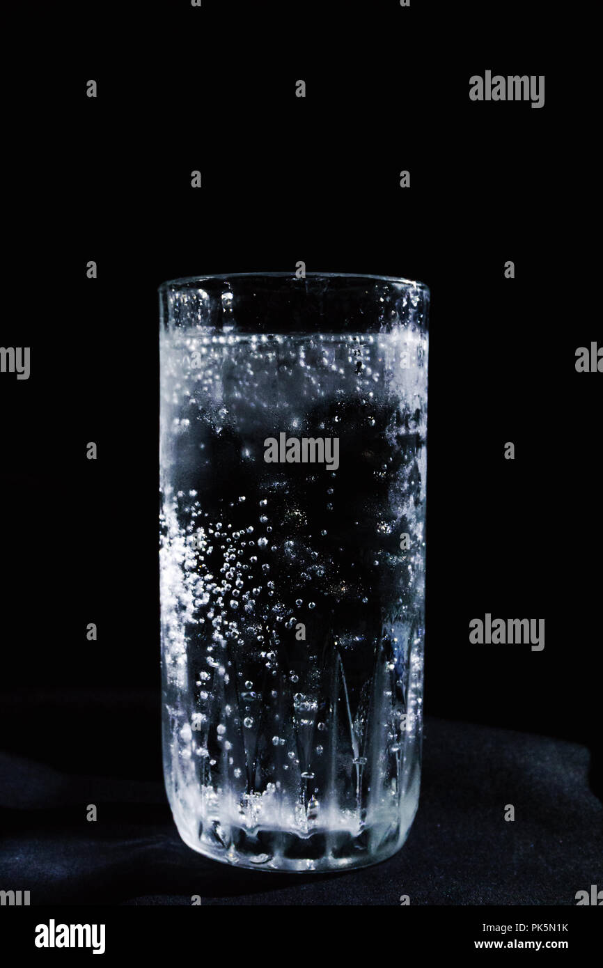 Soda water in glass on black backdrop with light on top Stock Photo - Alamy