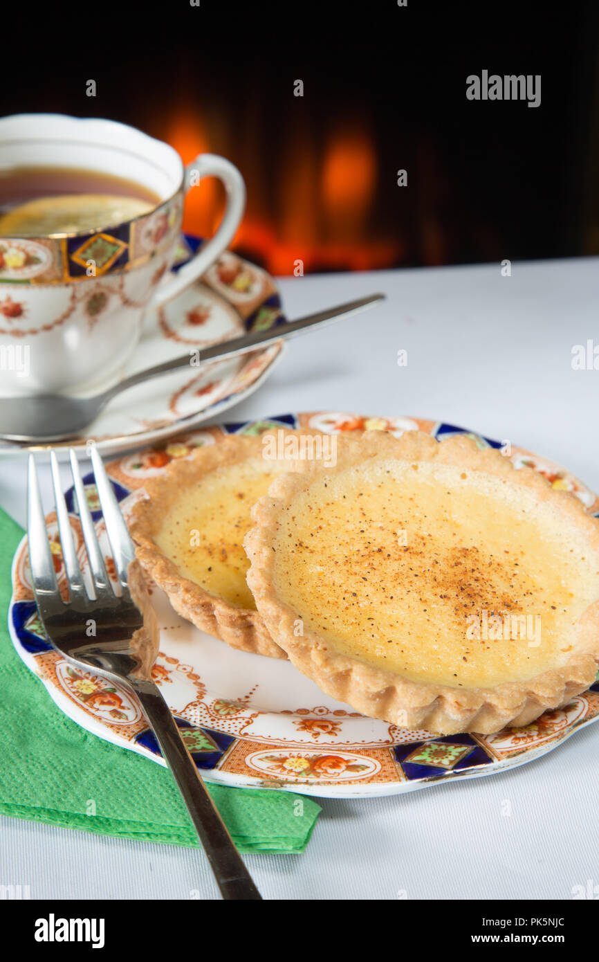 An English high tea of homemade Custard tart with lemon tea served on ...