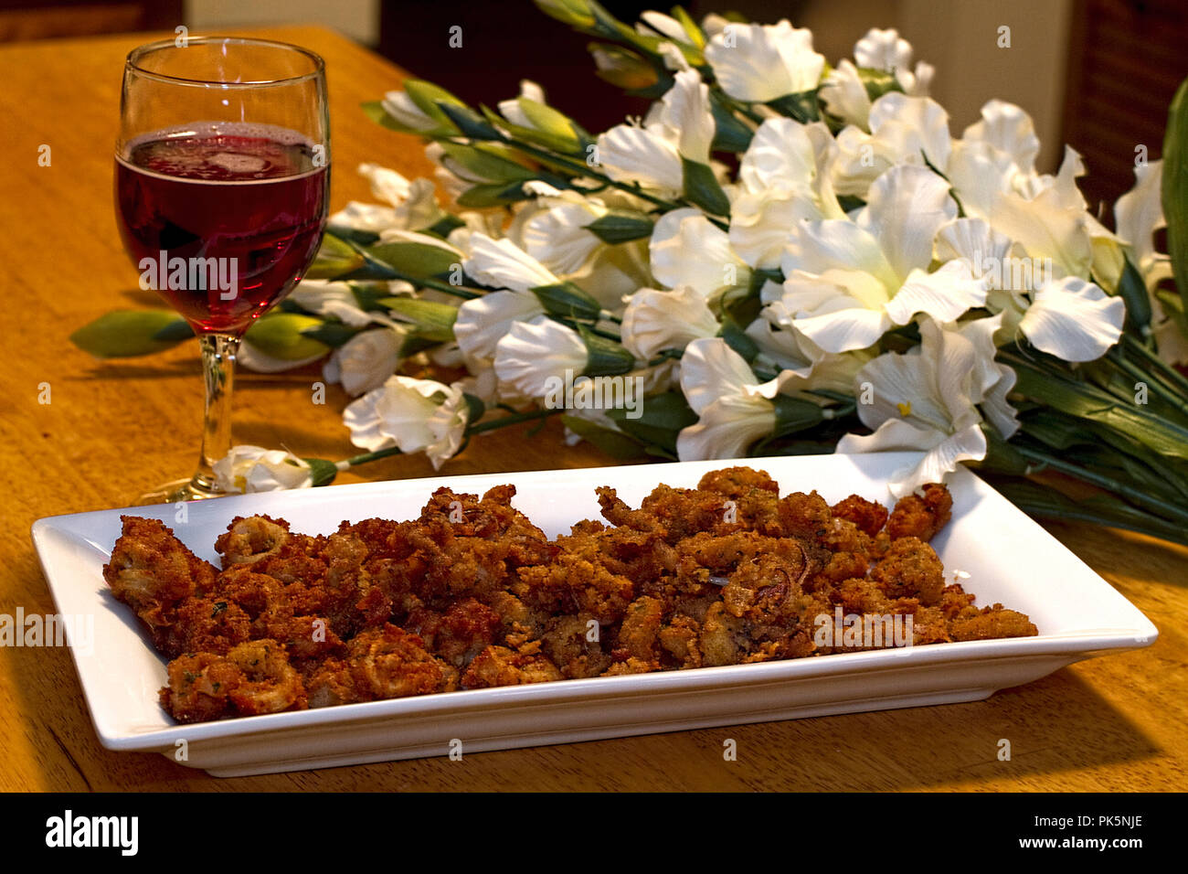 Fried calamari beautifully served in white serving dish with wine glass ...