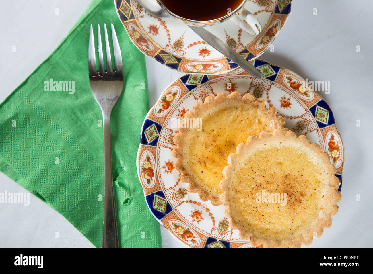 An English high tea of homemade Custard tart with lemon tea served on ...