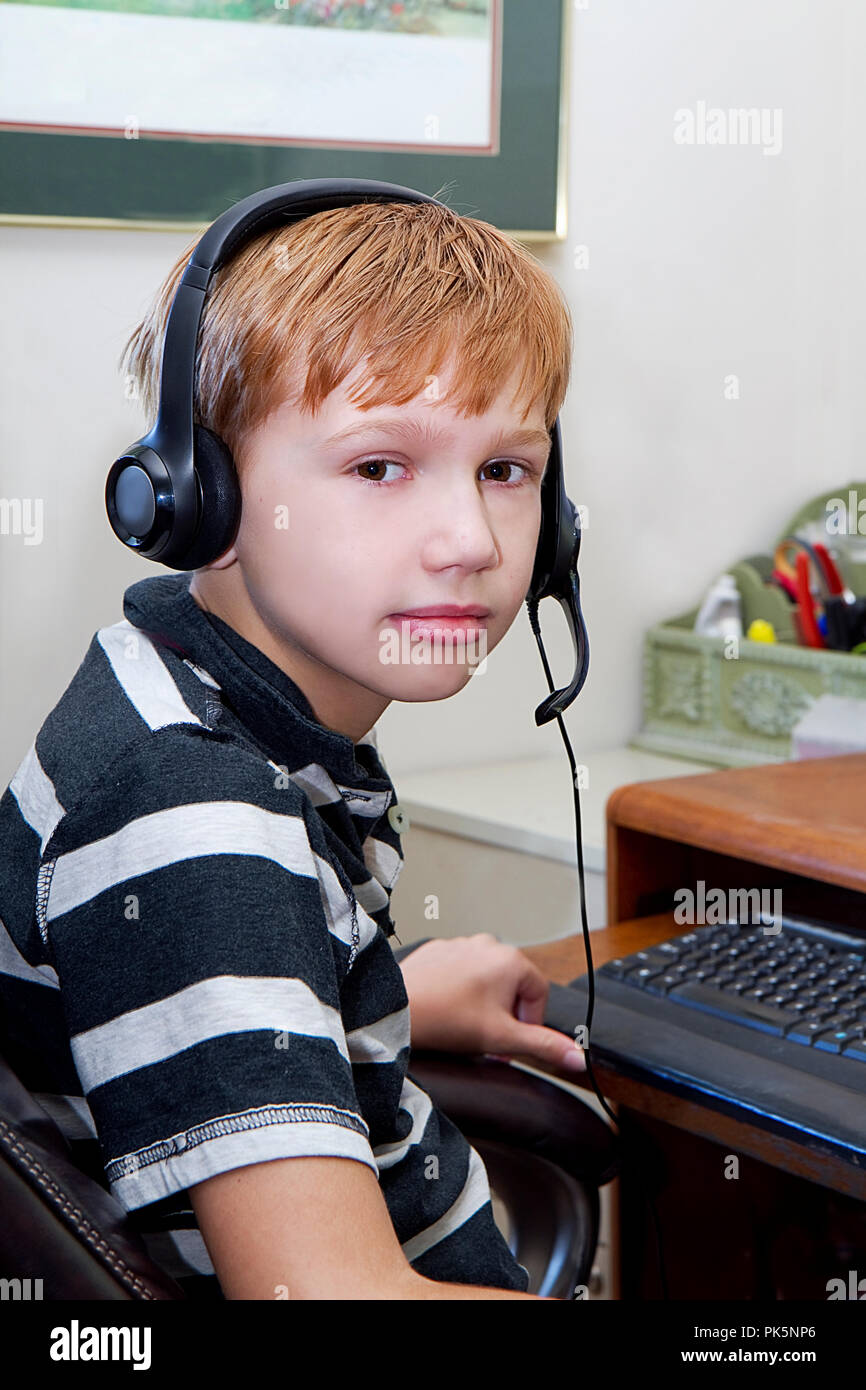 Young boy wearing headphones while working at computer Stock Photo - Alamy