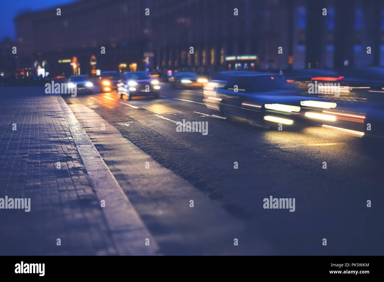 Night city street with approaching cars on the road, close up view from ...