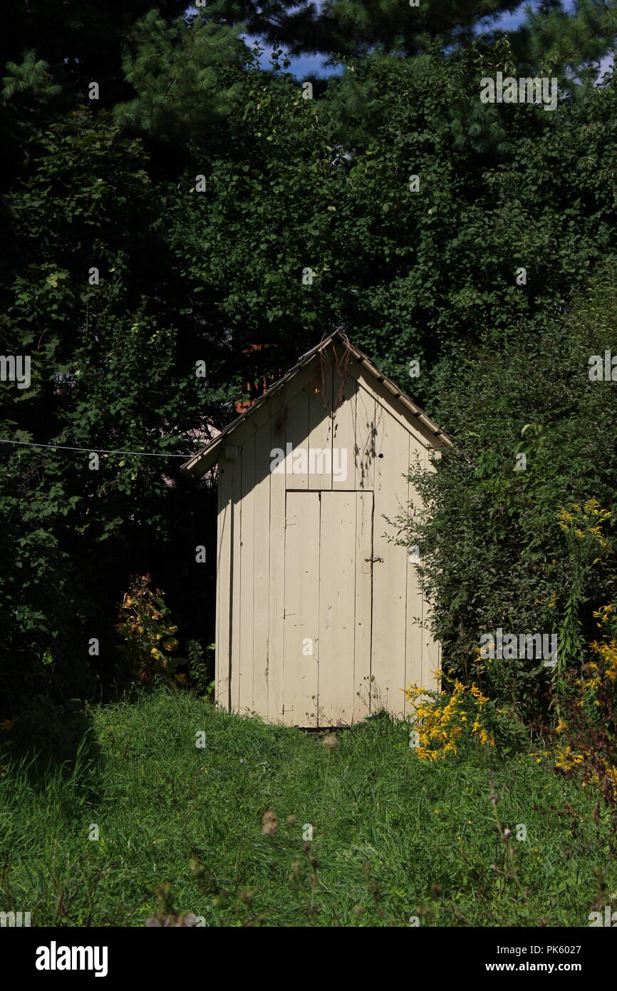 Vintage and authentic farm outhouse in the backyard on a late summer ...