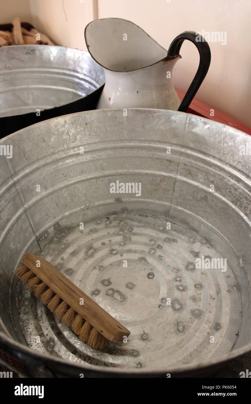 Metal washing basin, scrubbing brush, and water pitcher on a late ...