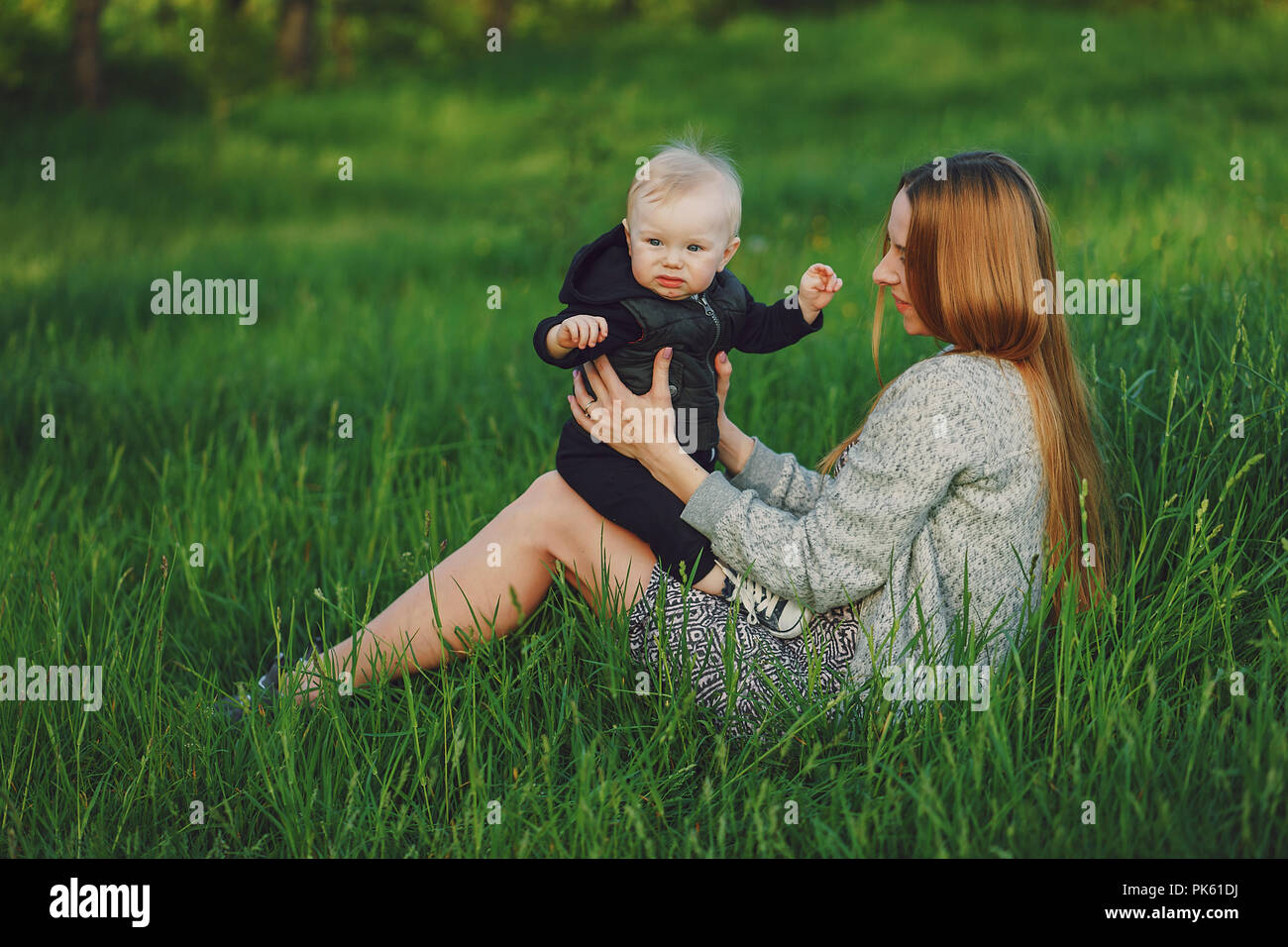 beautiful long-haired young mother in the summer sunshine park are ...