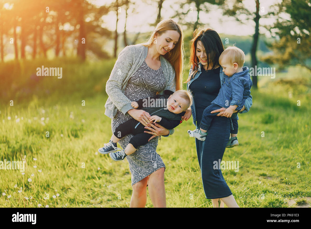 Two beautiful long-haired young women in the summer sunshine park are ...