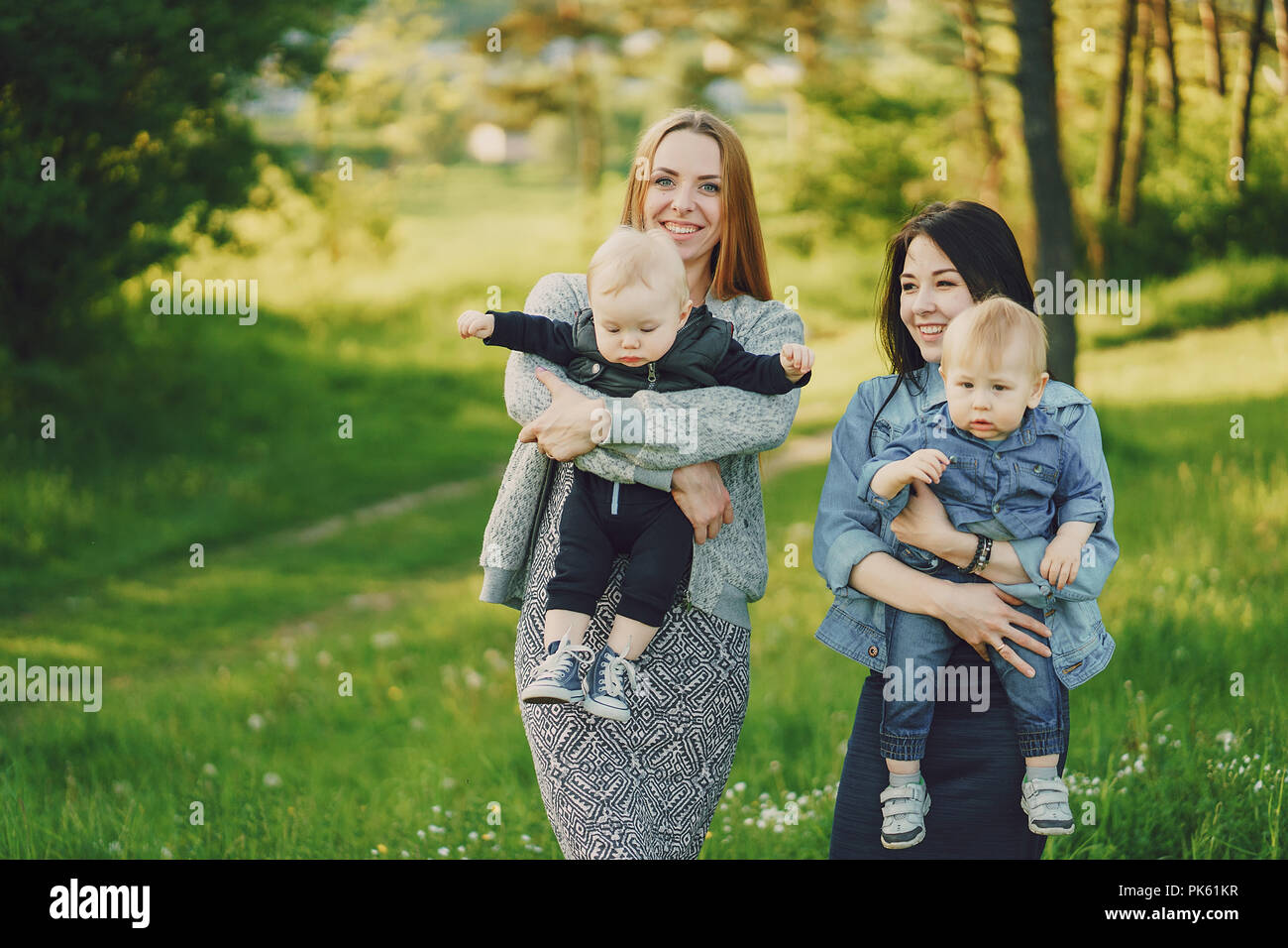 Two beautiful long-haired young women in the summer sunshine park are ...