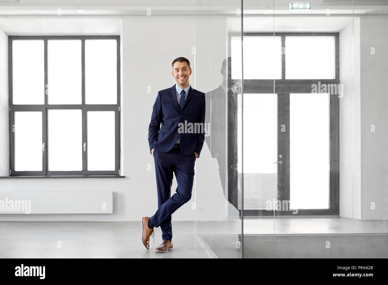 smiling businessman at office glass wall Stock Photo - Alamy