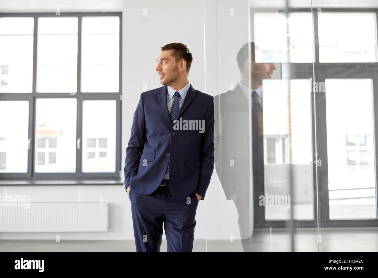 smiling businessman at office glass wall Stock Photo - Alamy