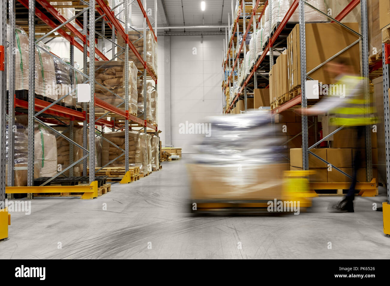 worker carrying loader with goods at warehouse Stock Photo - Alamy