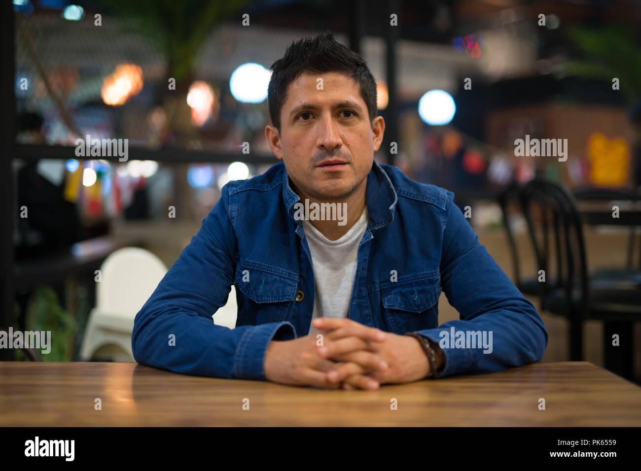 Hispanic man thinking while relaxing at the restaurant Stock Photo - Alamy