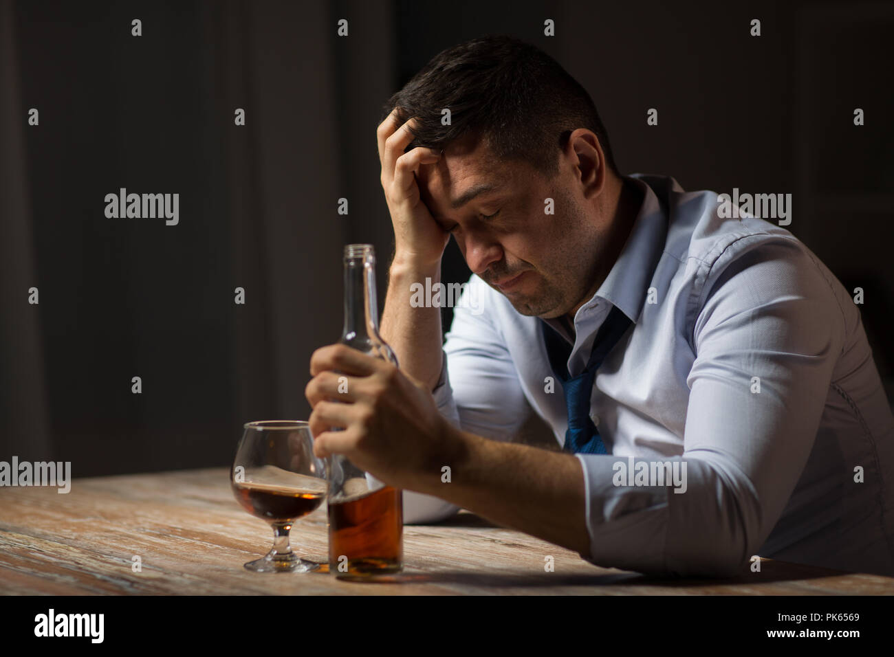 drunk man drinking alcohol at table at night Stock Photo - Alamy