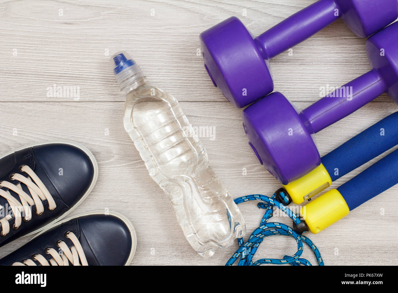 Different tools for fitness with bottle of water in room or gym on grey ...
