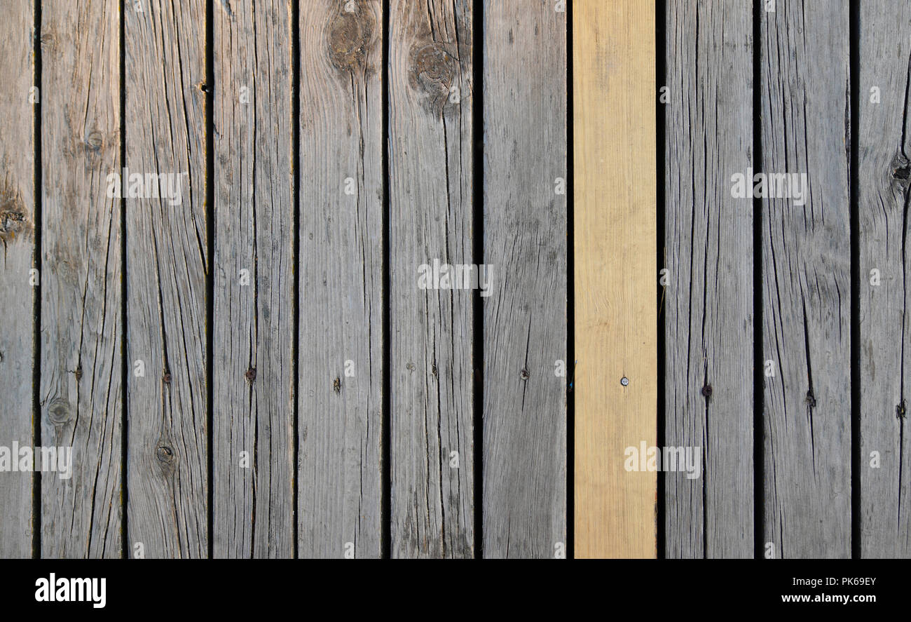 One new wooden plank among old wooden planks. Concept of replace and ...