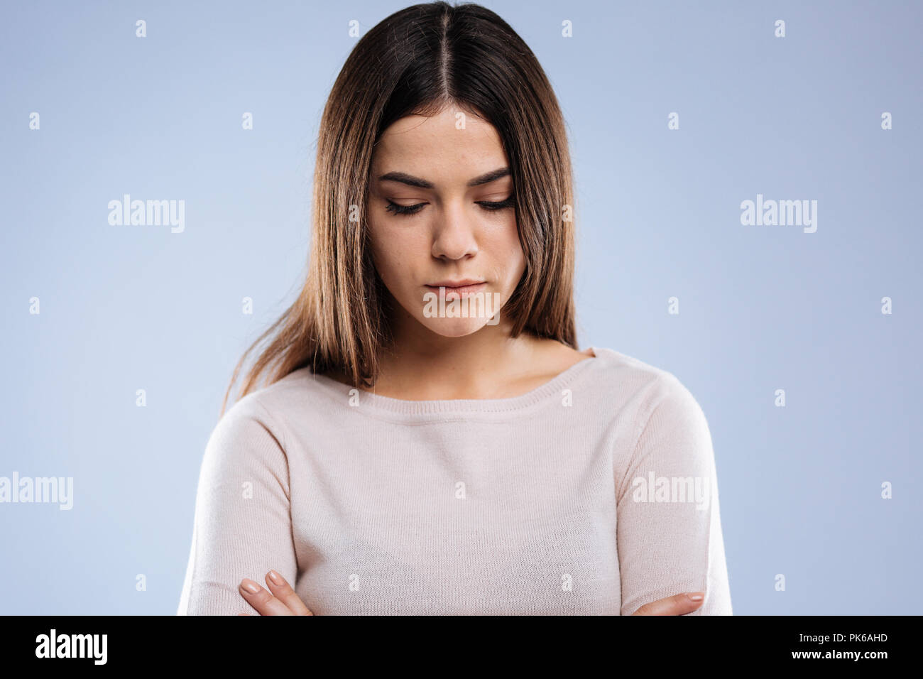 Nice young woman looking down while being sad Stock Photo - Alamy