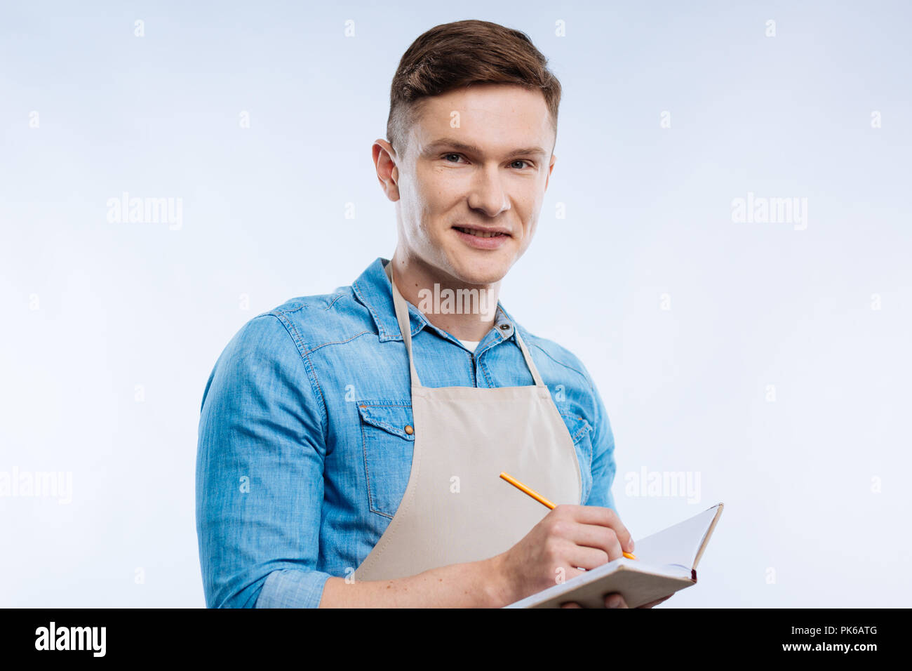 Cheerful nice man writing with a pencil Stock Photo - Alamy