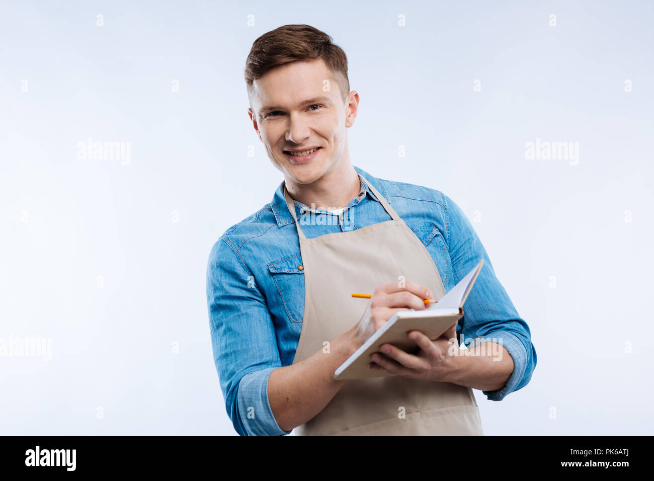Positive joyful man writing in his notebook Stock Photo - Alamy