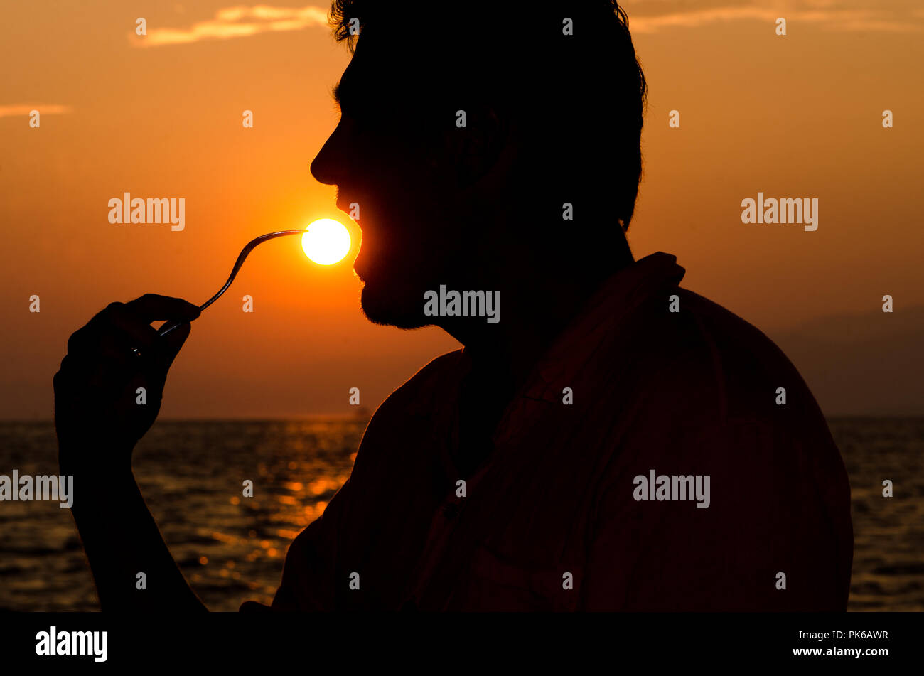 Eating the sun. Silhouette of a man on the seashore at sunset Stock ...