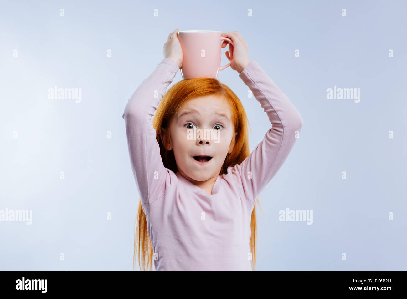 Nice happy girl putting a cup on the head Stock Photo - Alamy