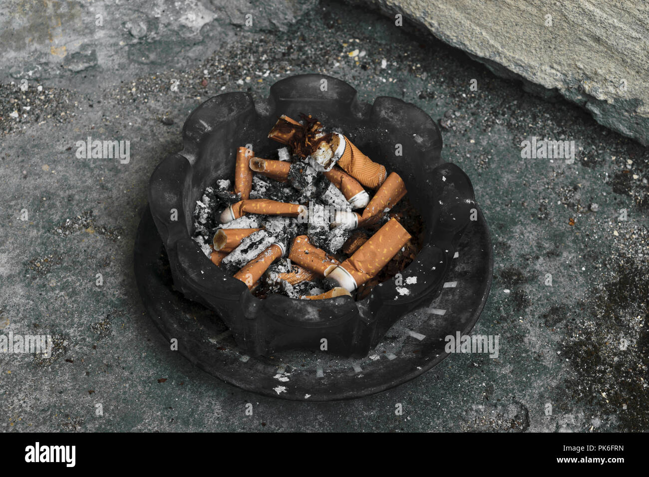 Background surface of ashtray with smoked cigarettes placed on concrete ...