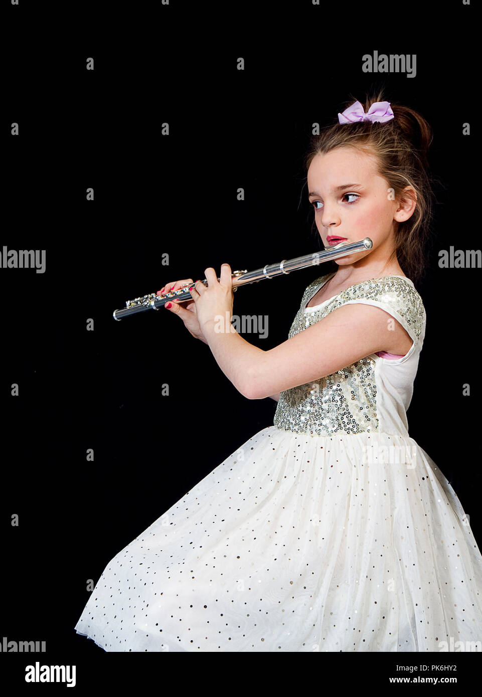 Sweet and beautiful young girl playing her flute isolated on black ...