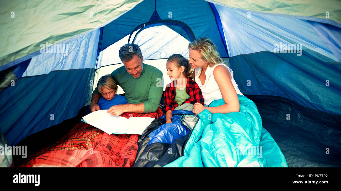 Family reading book in the tent Stock Photo - Alamy