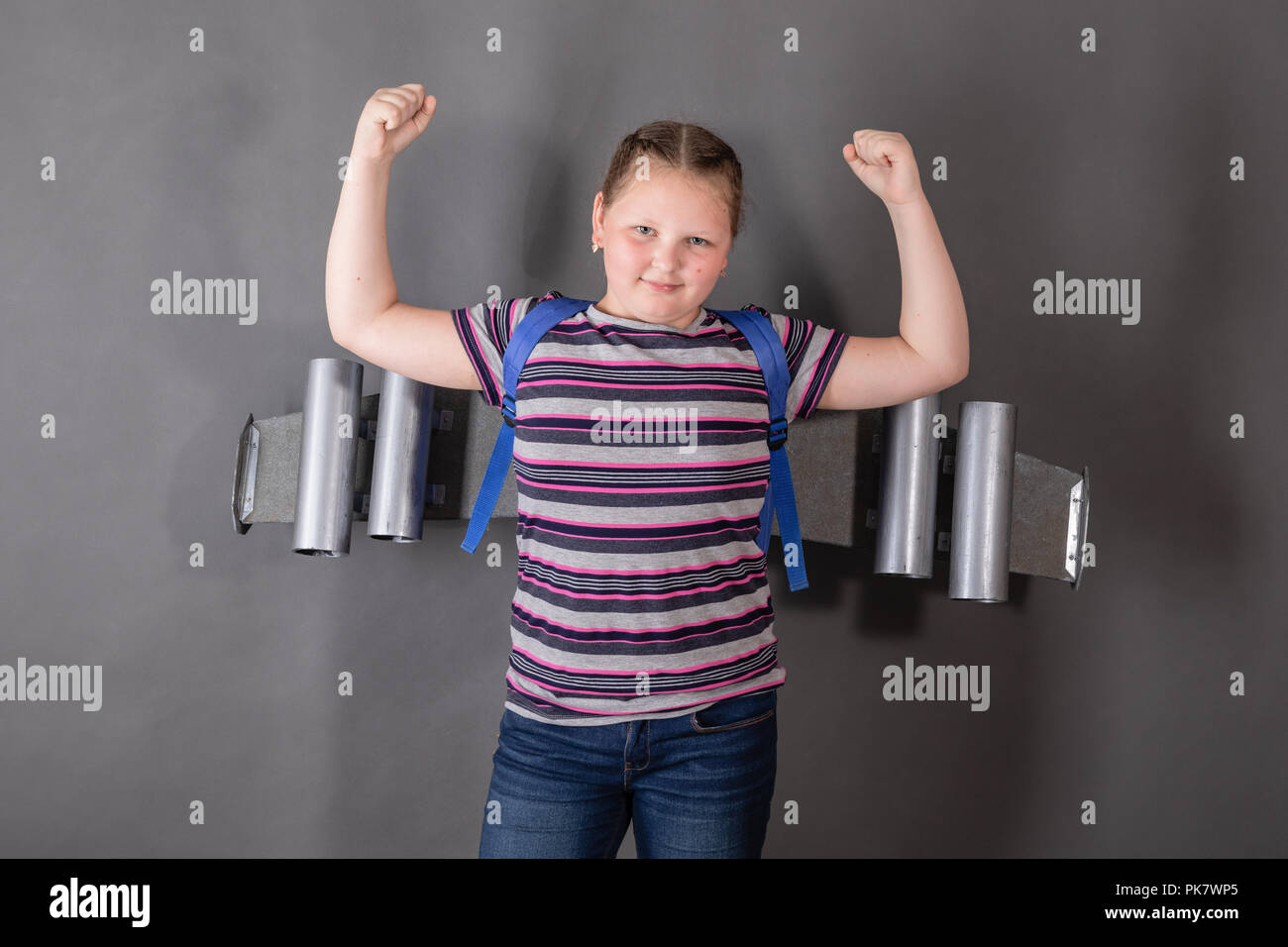 Strong stout little girl with a jetpack on his back on gray background ...