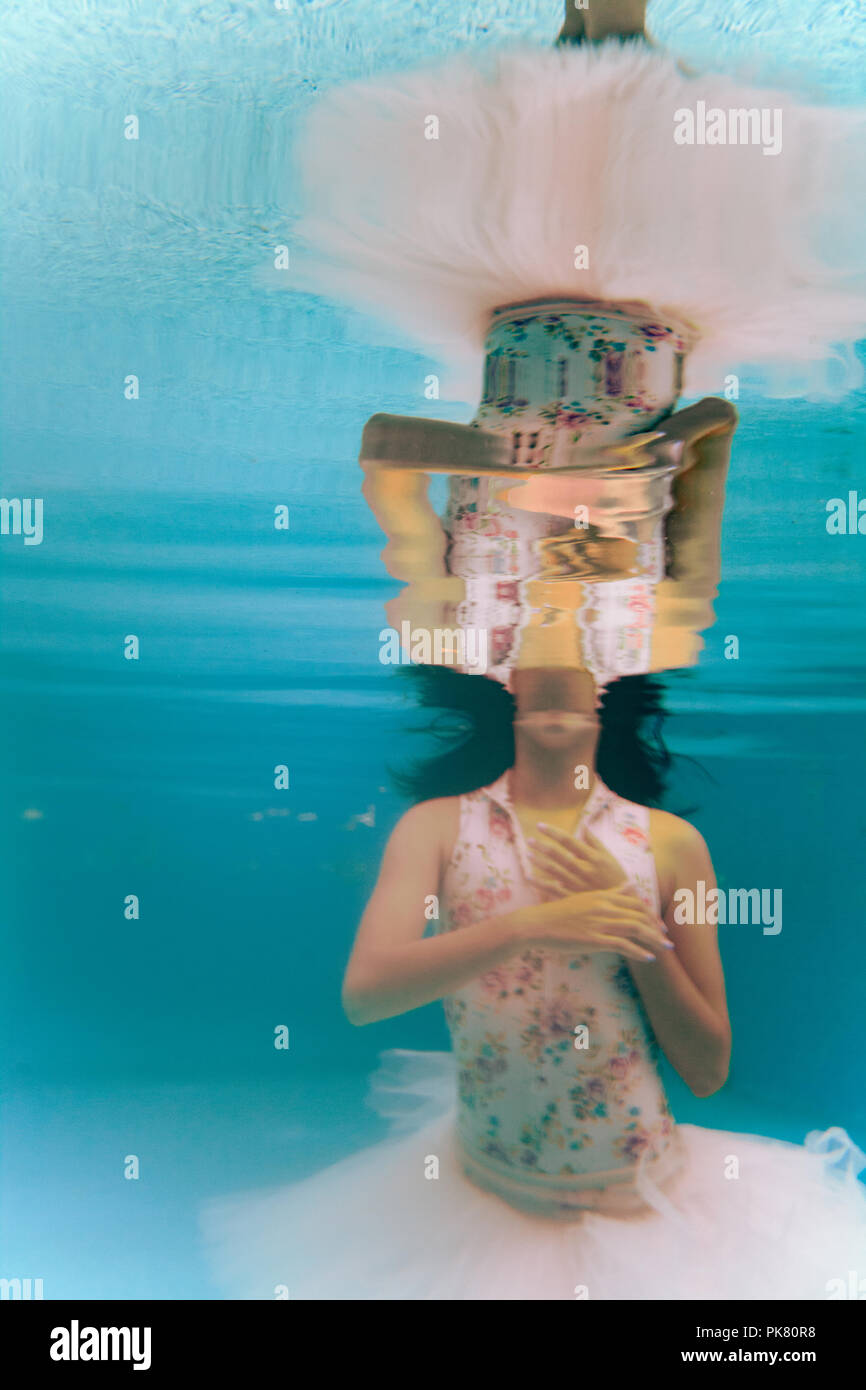 Ballerina is dancing under water. Her reflection in water is visible ...