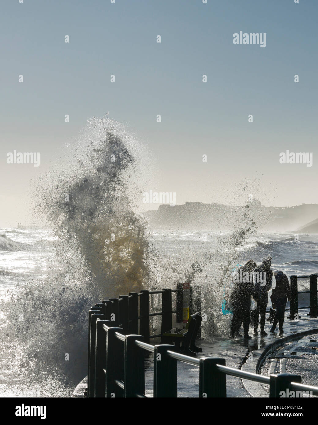 High tide and huge waves crashing over the sea wall and people at ...