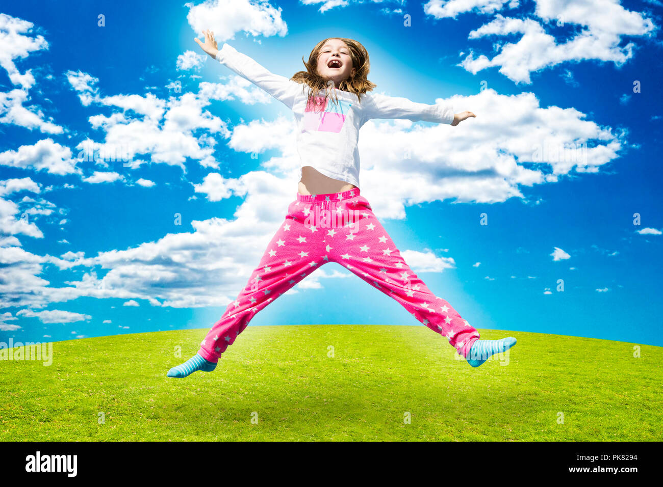 Happy girl jumping high on a green grass during sunny day Stock Photo ...