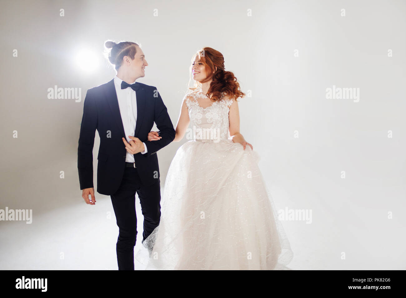 Laughing bride and groom look at each other, dance and jump with ...