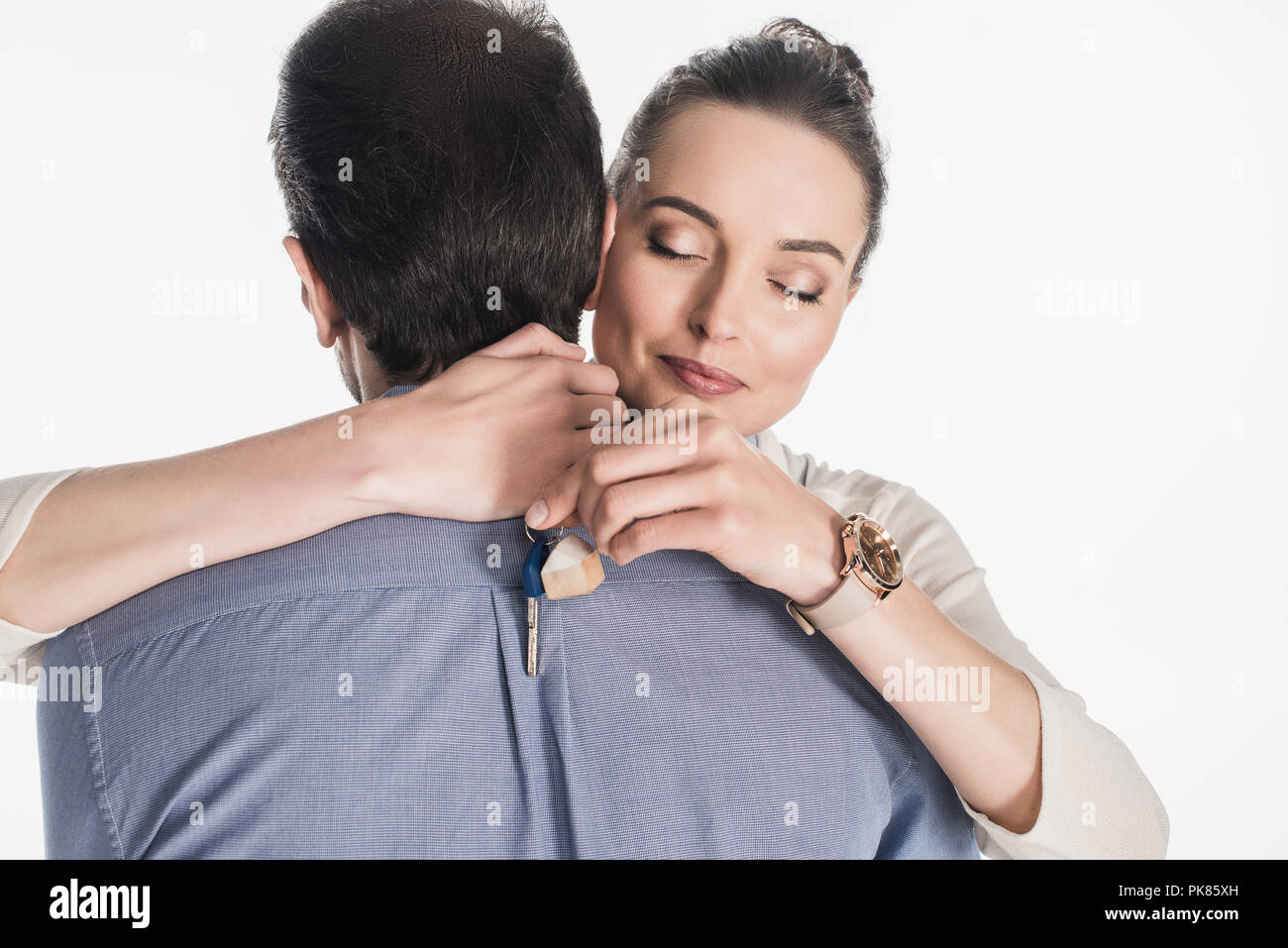 partial view of woman with key from new house hugging husband isolated ...