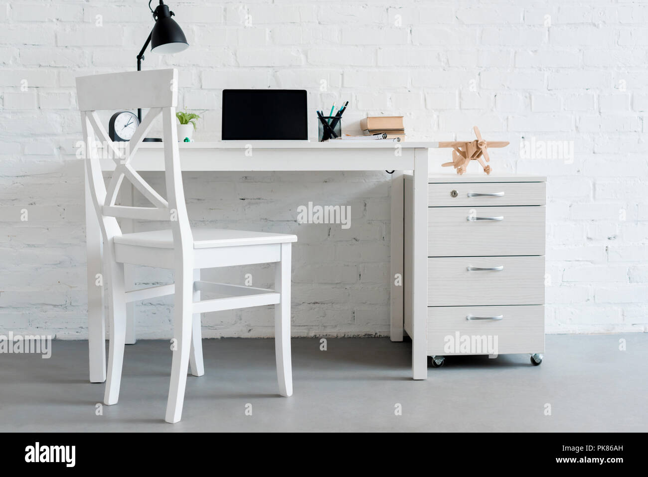 modern work desk with laptop at home in front of white brick wall Stock ...