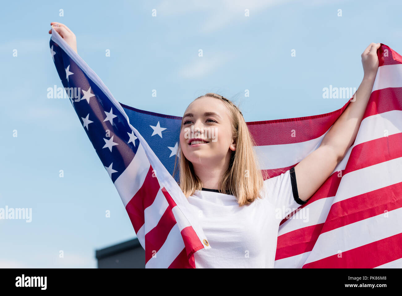 happy teen girl with usa flag in front of blue sky Stock Photo - Alamy