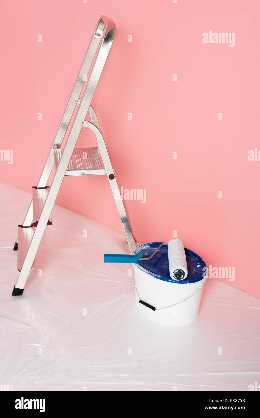 close up view of paint roller on paint tin and ladder in front of ...