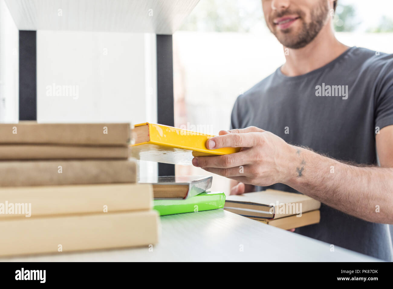 cropped shot of smiling man putting books on shelves at home Stock ...