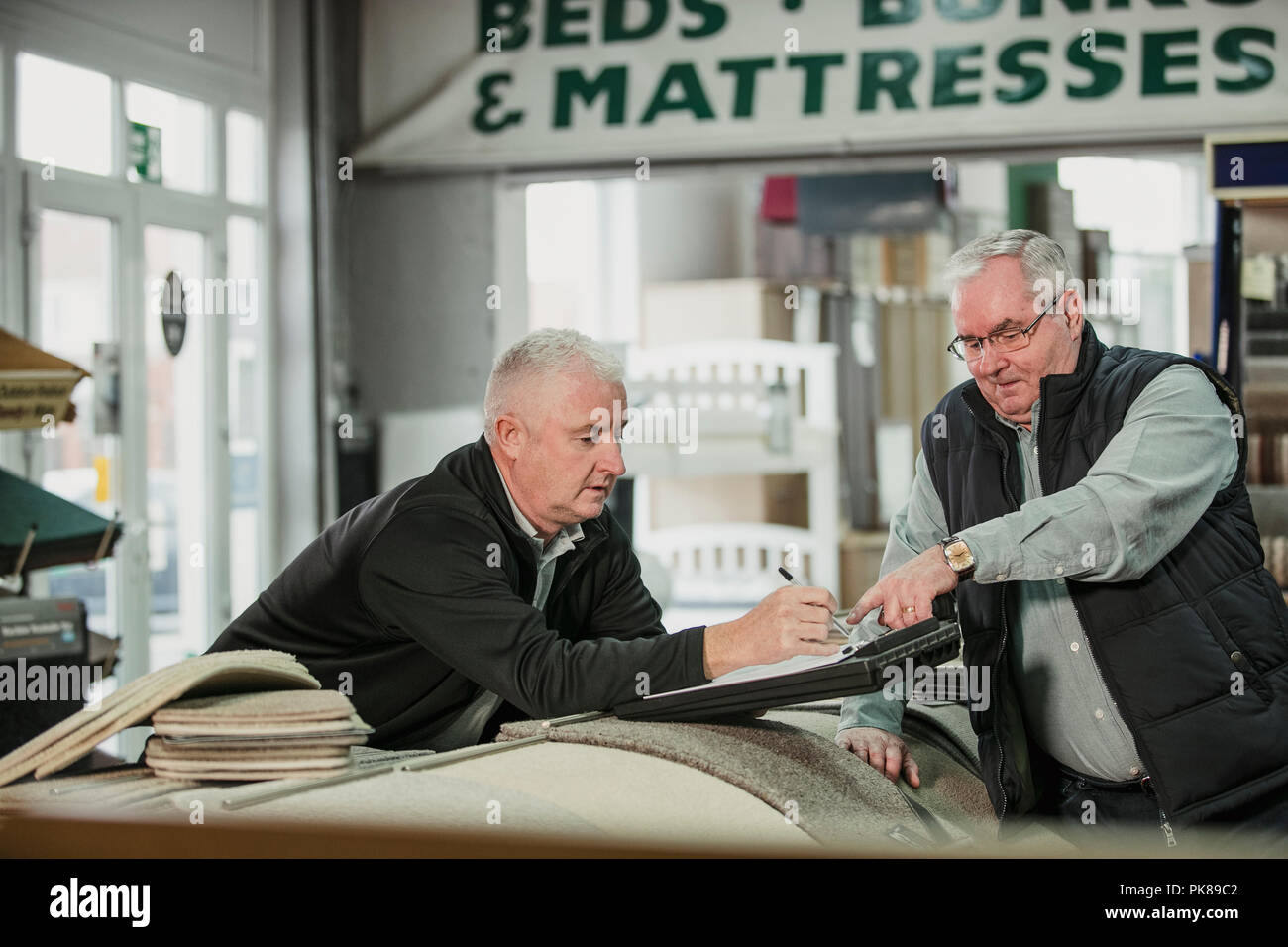 Two carpet business owners are discussing stock in their shop Stock ...