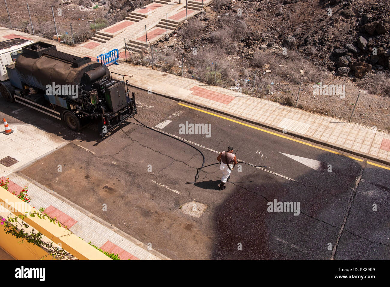 Workman spraying tar on to a road in preparation for a new layer of ...