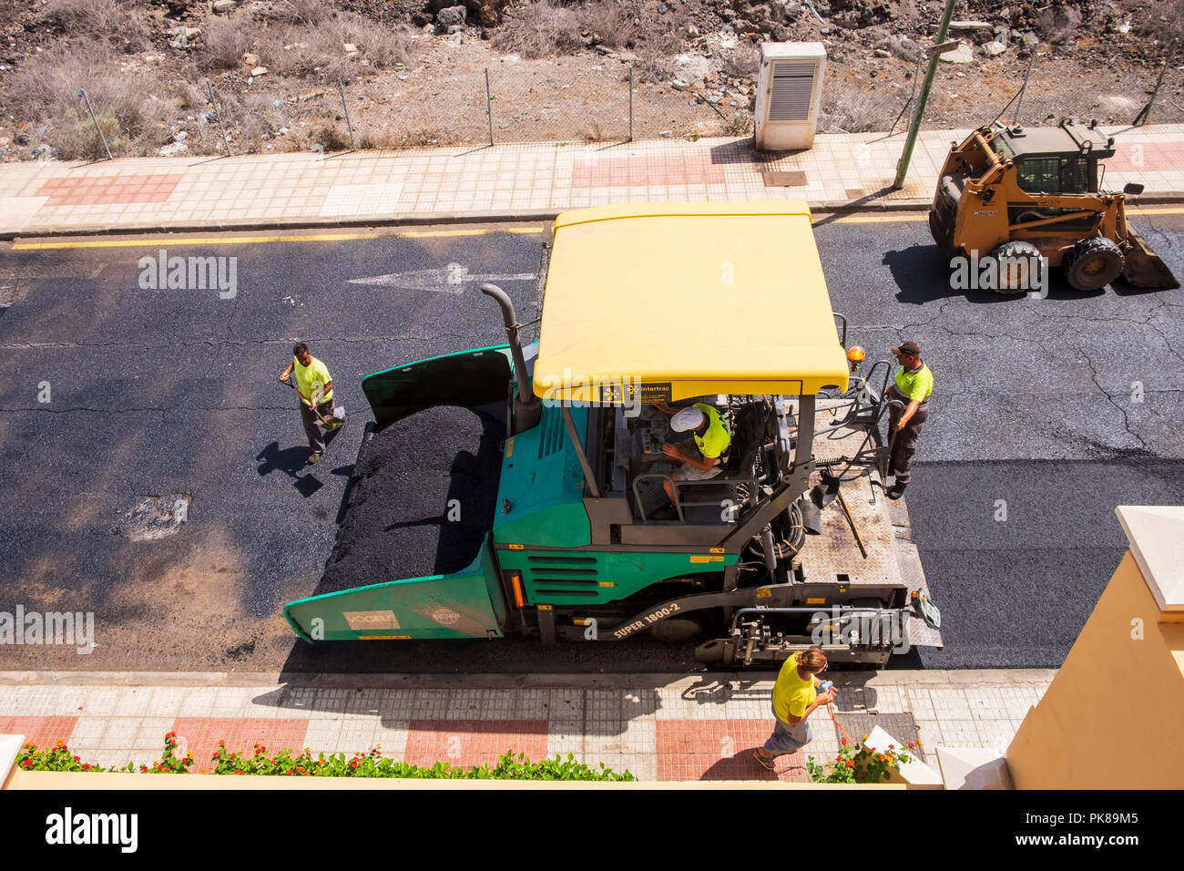Asphalt spreading machine laying down a new layer of tarmac on the road ...