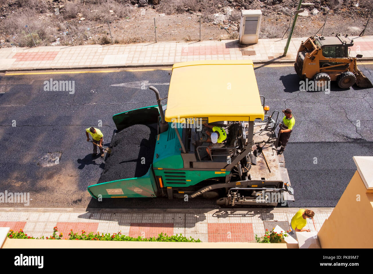 Asphalt spreading machine laying down a new layer of tarmac on the road ...