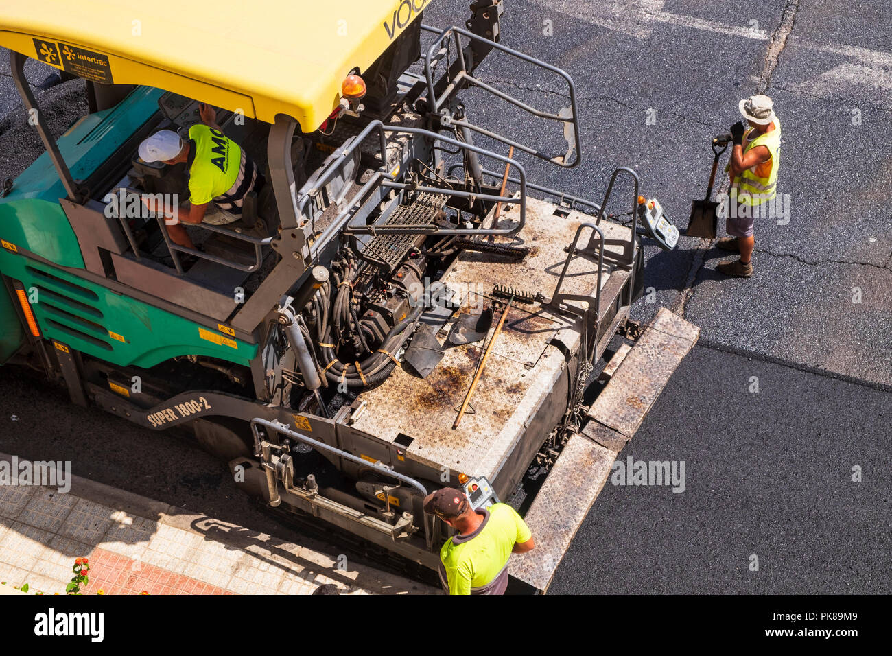 Asphalt spreading machine laying down a new layer of tarmac on the road ...