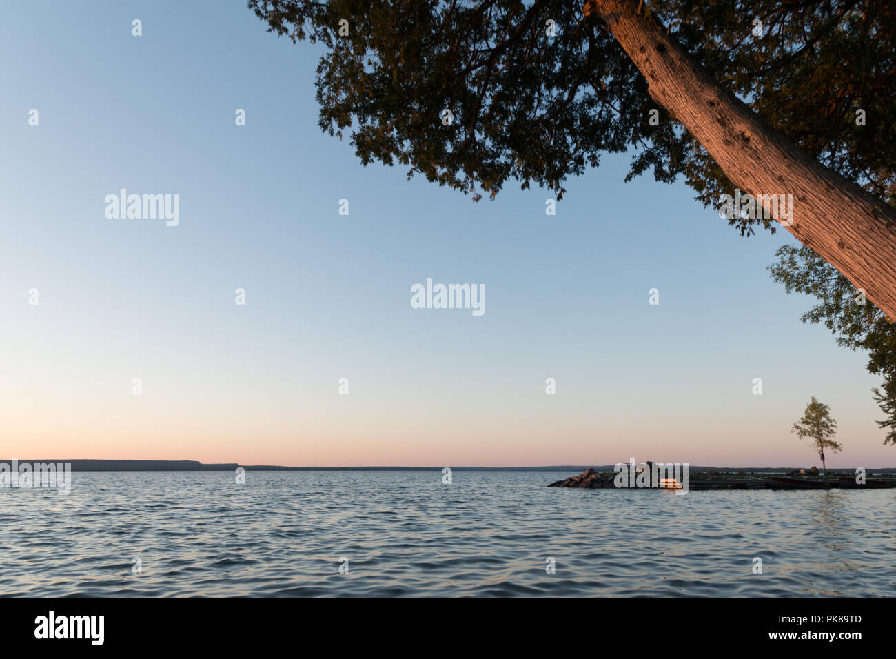 Lake Manitou shoreline sunset landscape with cedar trees and orange sky ...