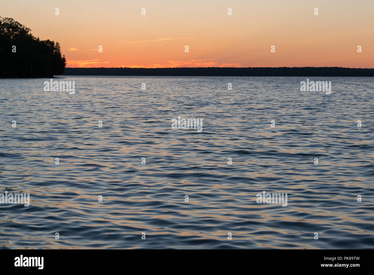 Lake Manitou shoreline sunset landscape with cedar trees and orange sky ...