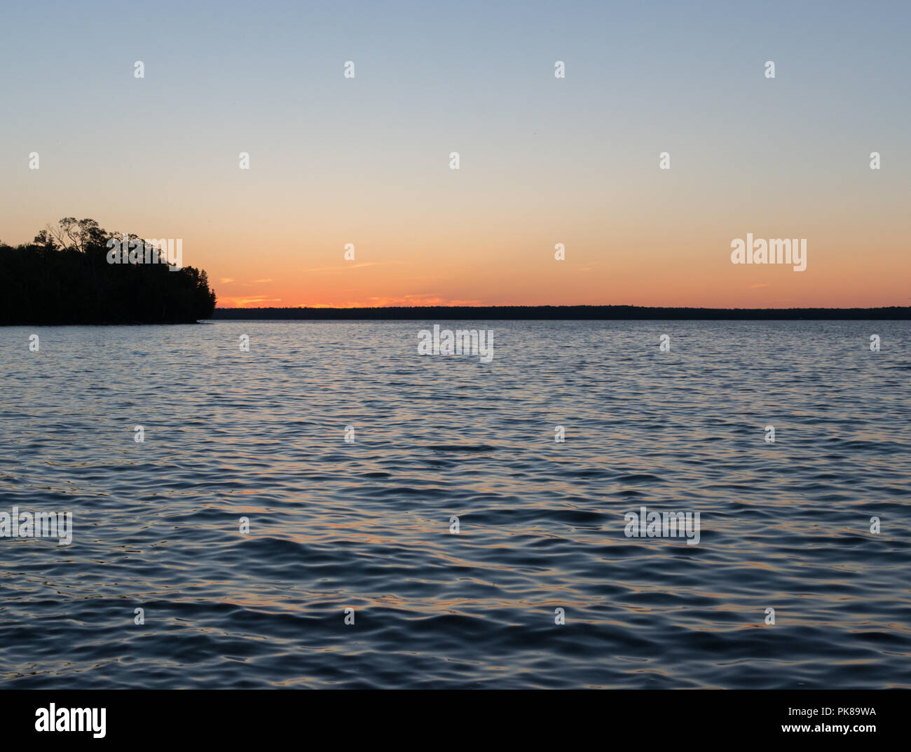 Lake Manitou shoreline sunset landscape with cedar trees and orange sky ...